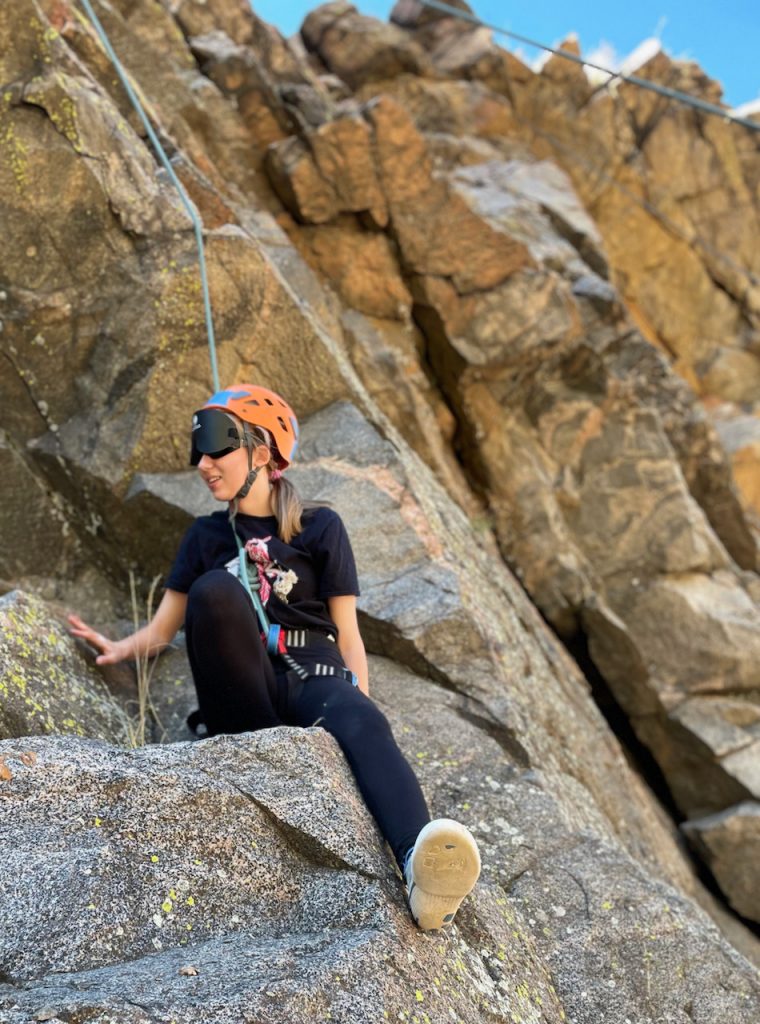 rc- Alexis, close-up sitting on ledge looking toward and feeling rock ...